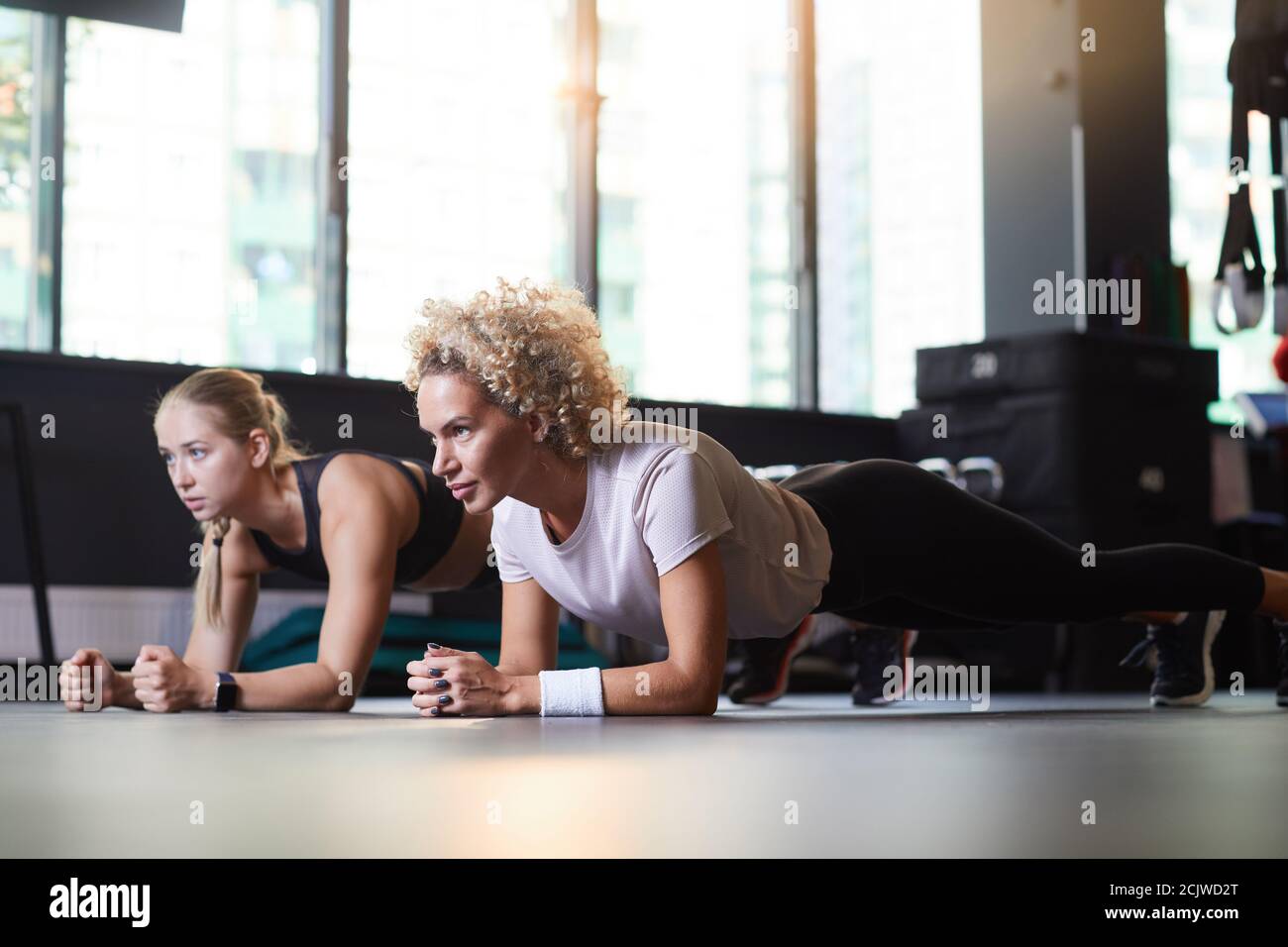 Two beautiful women exercising together on the floor during sports ...