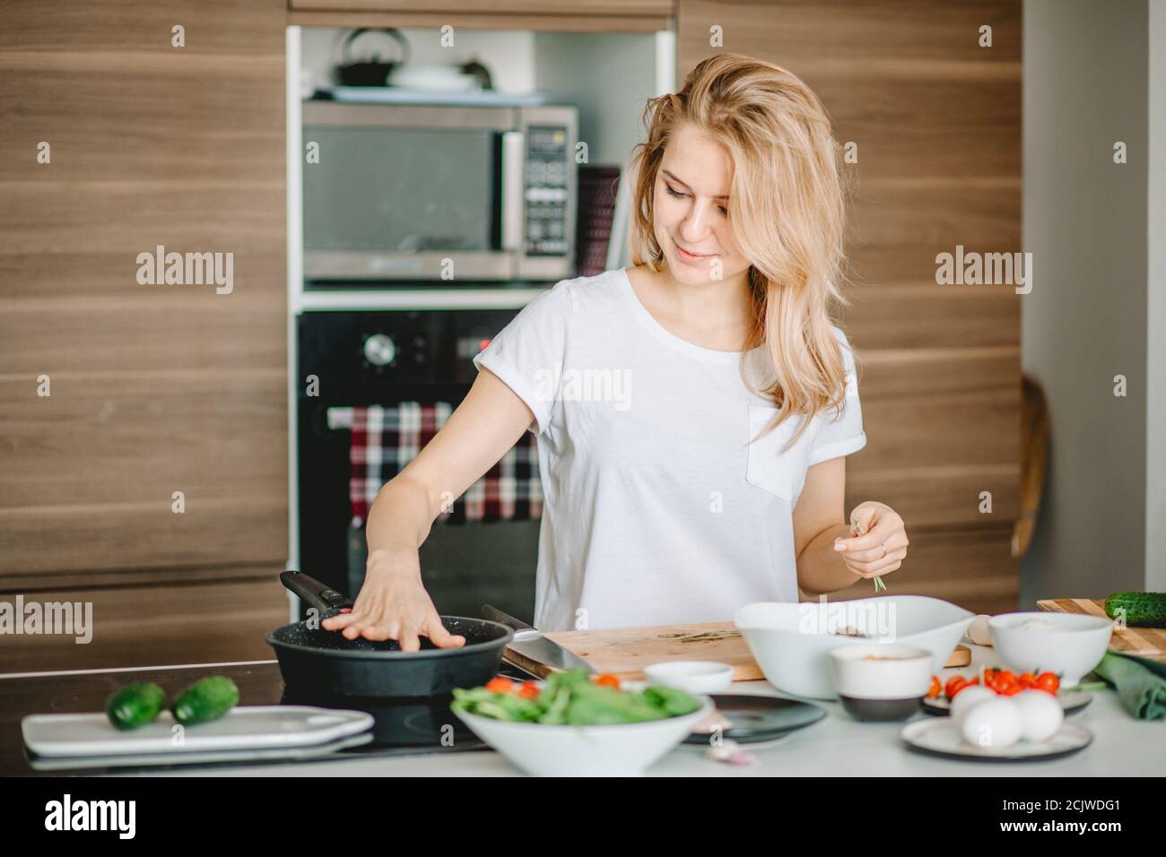 young blond girl checking the frying pan.check the new gas cooker ...