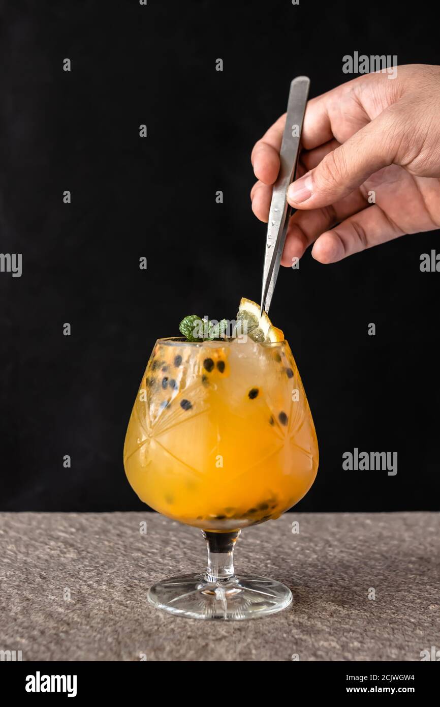 Vertical closeup shot of a bartender hand adjusting a cocktail with ...