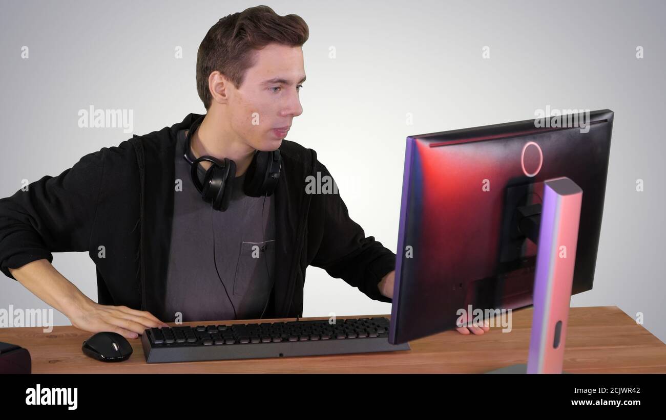 Nervous man watching video games on a PC computer on gradient ba Stock ...