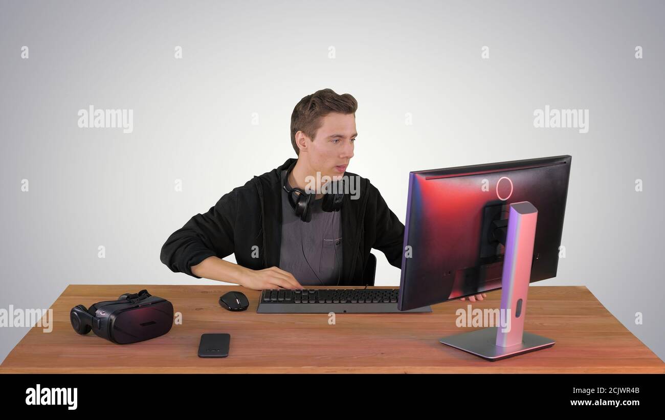 Nervous man watching video games on a PC computer on gradient ba Stock ...