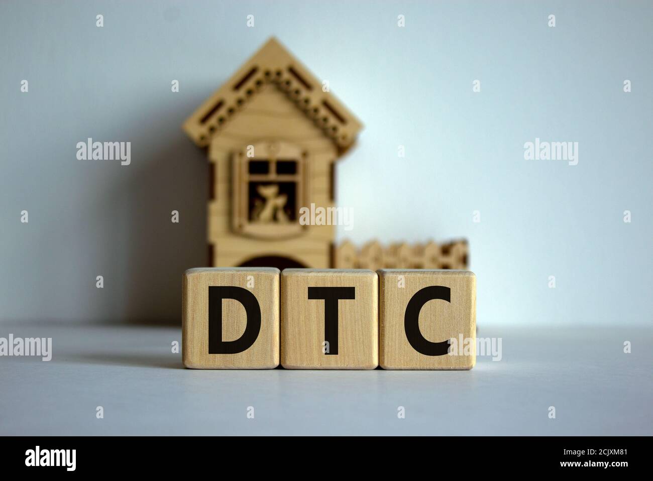 Wooden cubes form the word 'DTC' near miniature house. Beautiful white ...