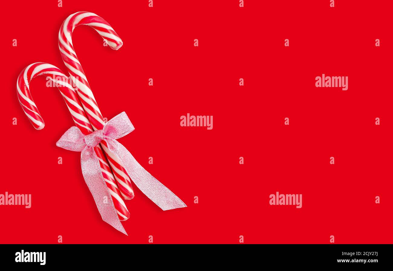 Christmas candy canes with ribbon isolated on red background with ...