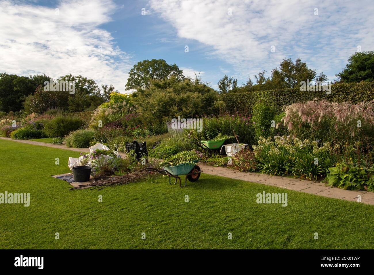 Garden as a wider landscape with wheelbarrows and border planting with ...