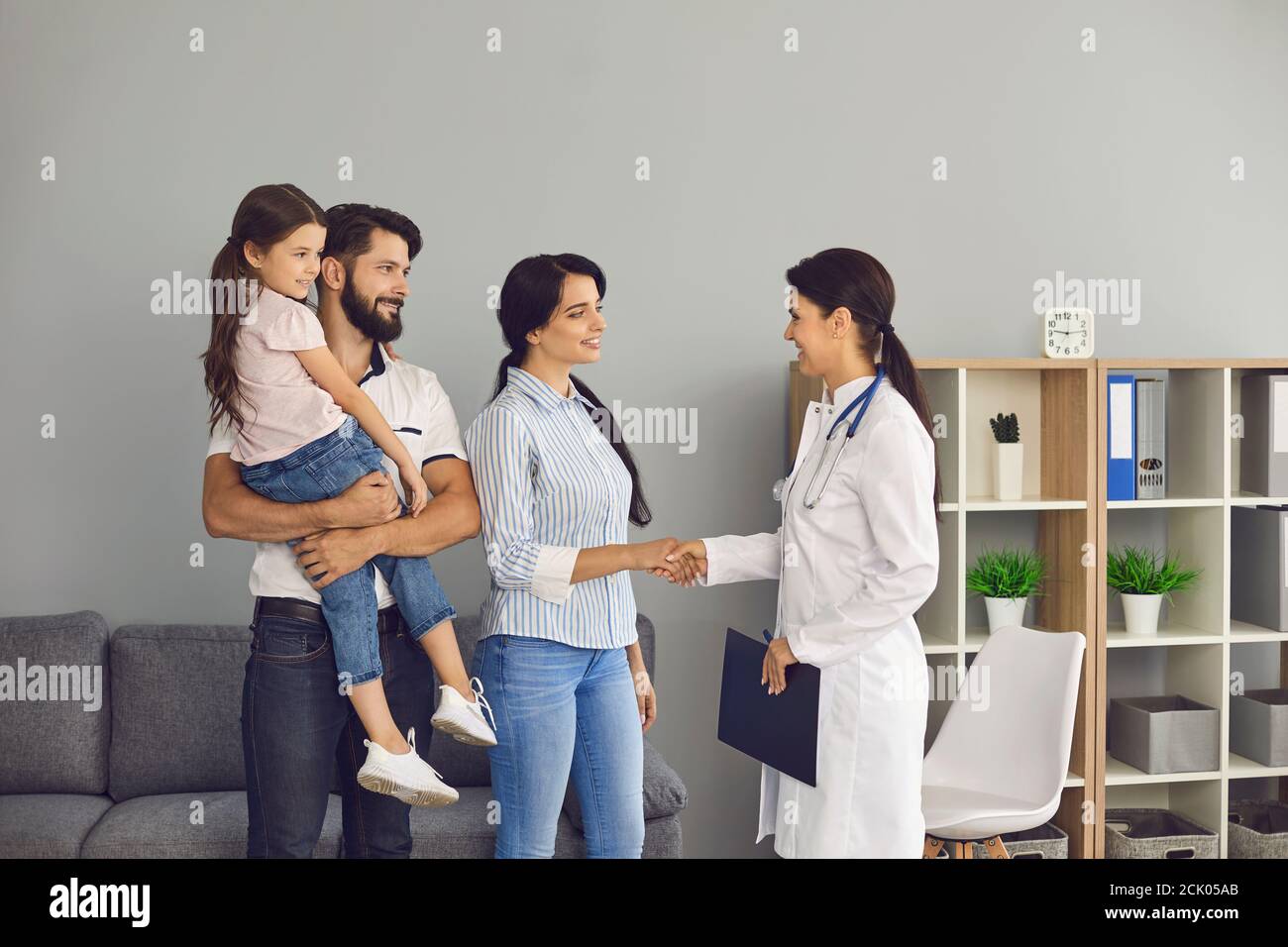 Happy family saying goodbye to woman doctor and shaking hands after ...