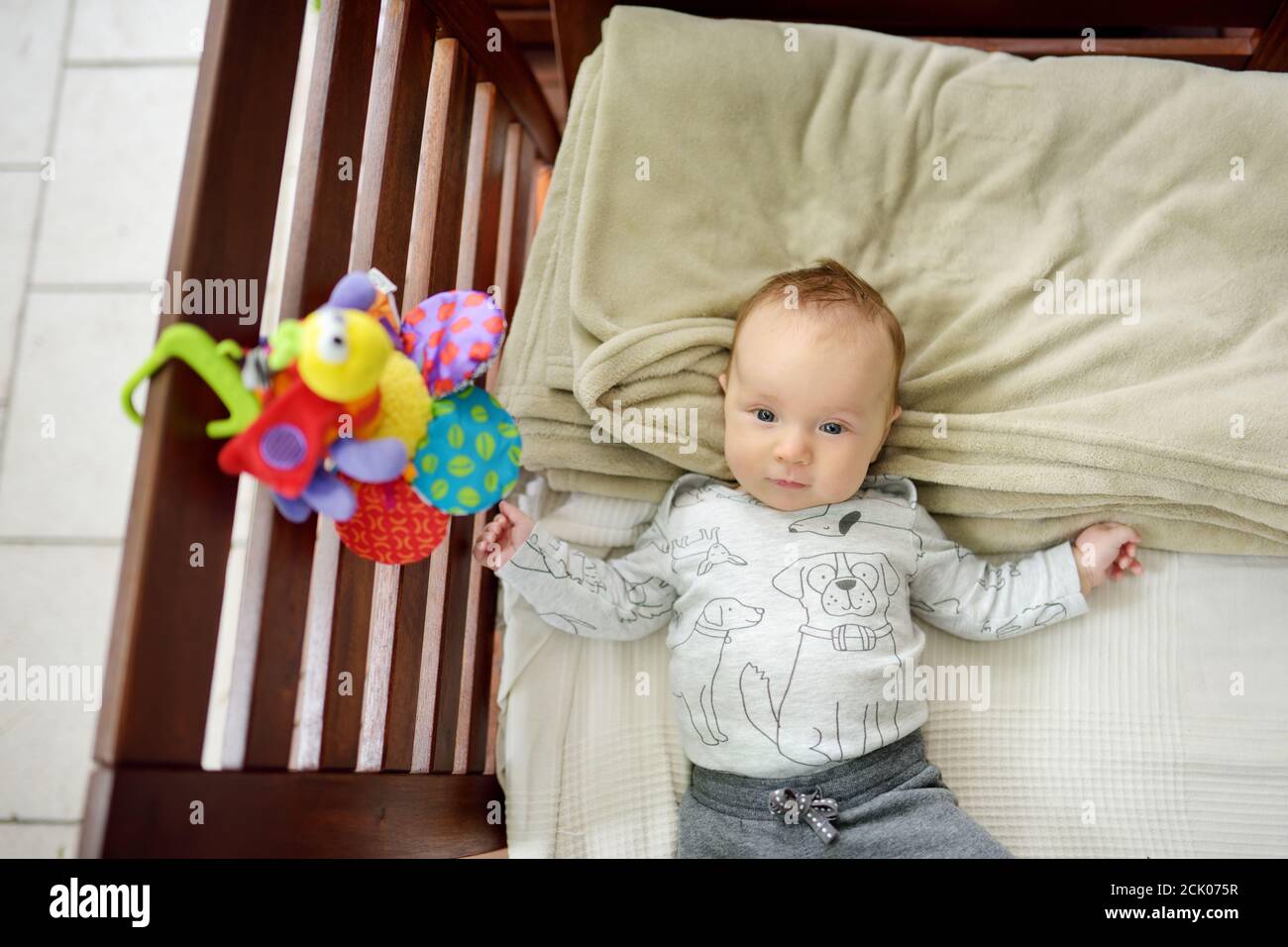 Cute three months old baby boy playing with his colourful toys outdoor ...