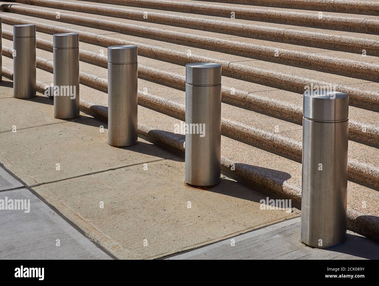 At the foot of steps to a plaza, stainless steel bollards limit ...