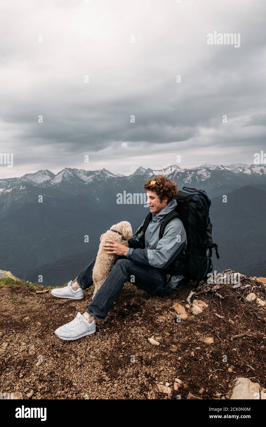 attractive backpacker with favourite pet on the mountain. side view ...