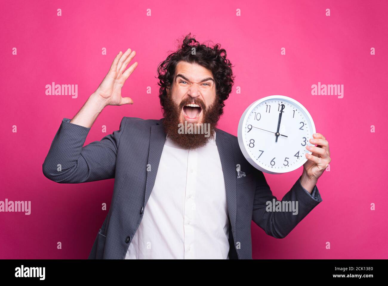 Portrait of angry business man screaming and holding CLOCK, delay ...