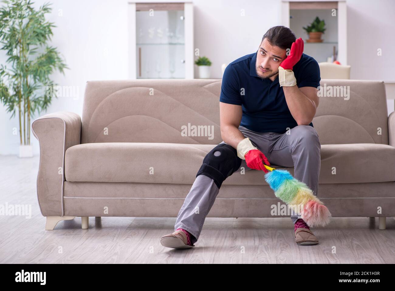 Young leg injured contractor cleaning house Stock Photo - Alamy