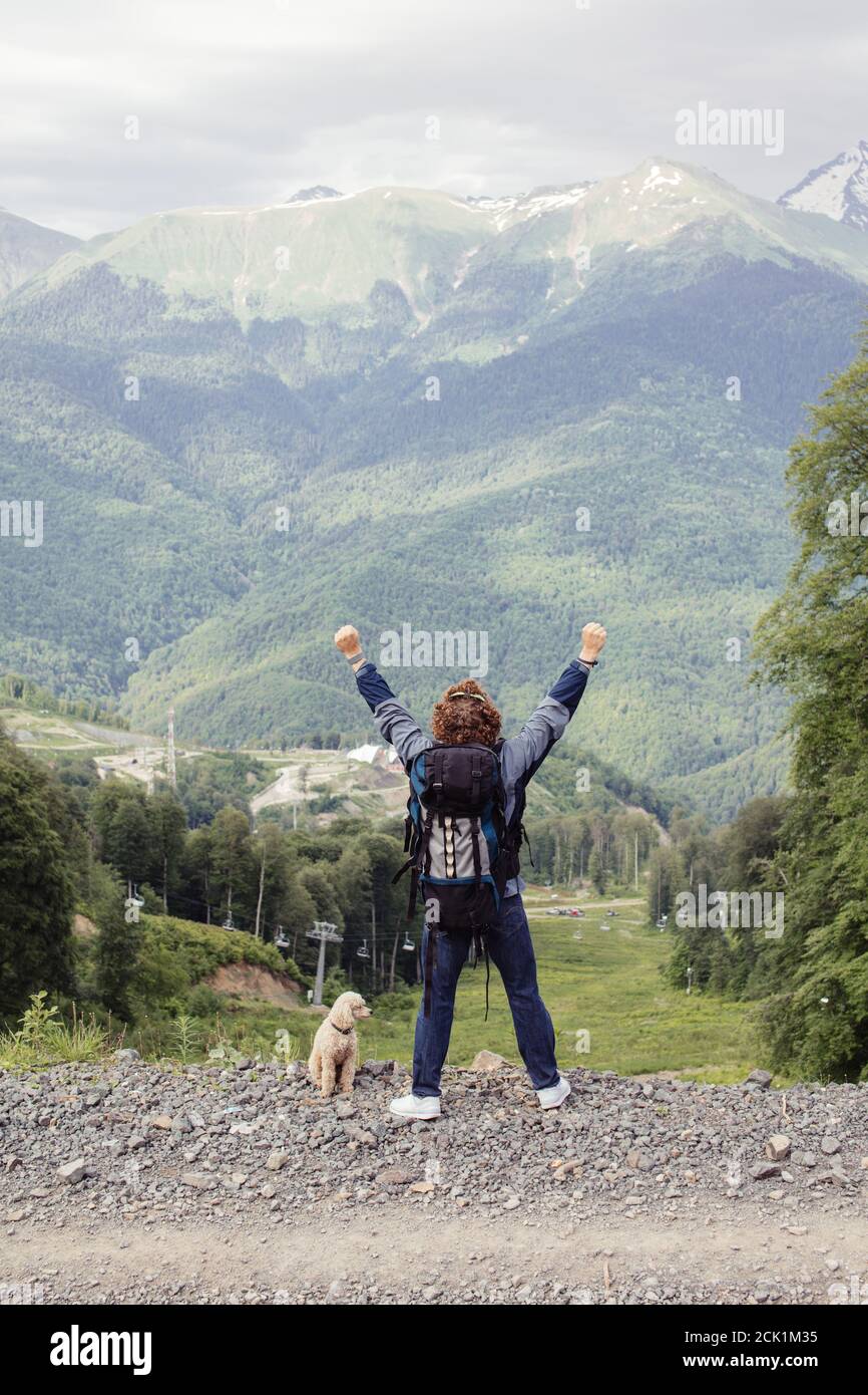 adventurous guy is celebrating the climbing to the peak.back view full ...