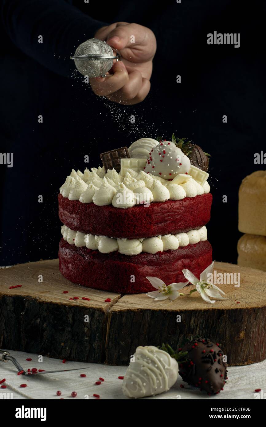 Vertical shot of a person pouring sugar powder on a fancy small red ...