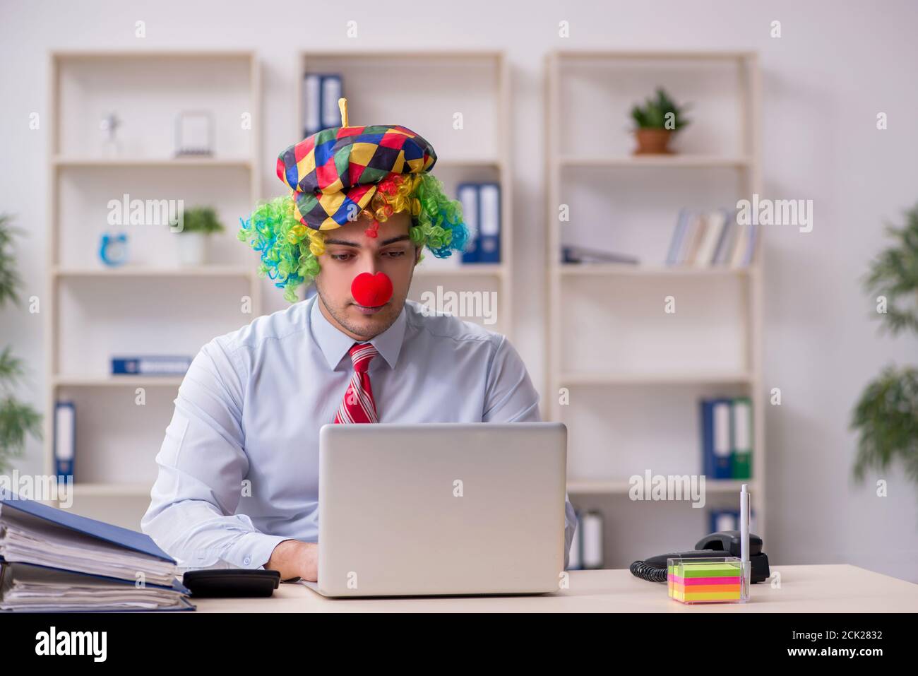 Funny employee clown working in the office room Stock Photo - Alamy