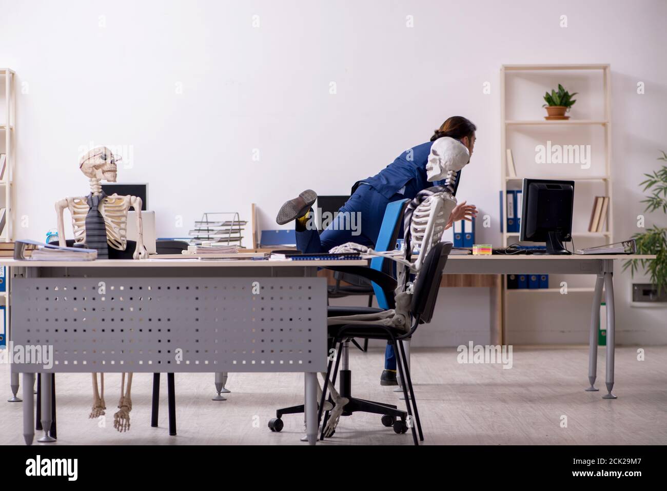 Young employee with skeletons in the office Stock Photo - Alamy