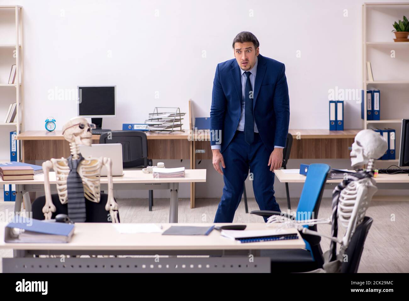 Young employee with skeletons in the office Stock Photo - Alamy