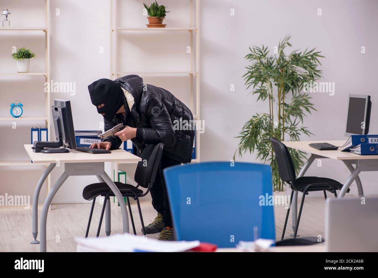 Young male burglar in the office room Stock Photo - Alamy