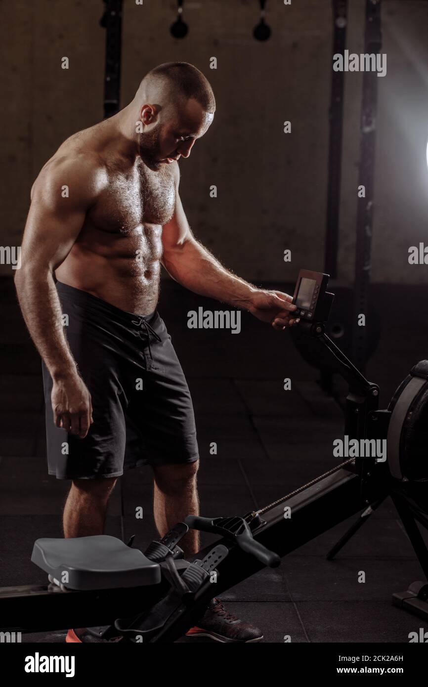 brutal bodybuilder controlling the speed of training on the rowing ...