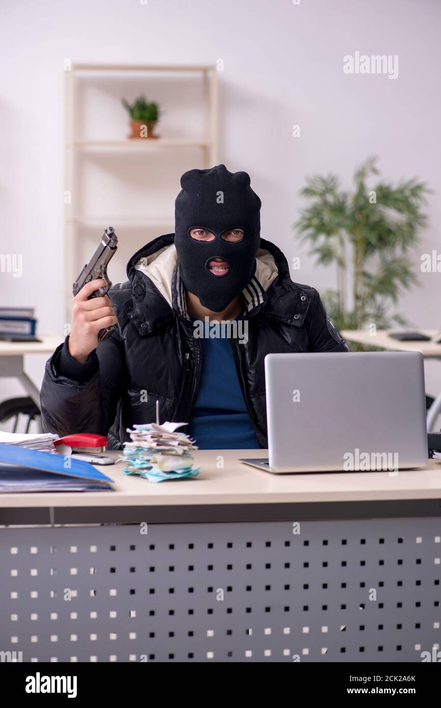 Young male burglar in the office room Stock Photo - Alamy