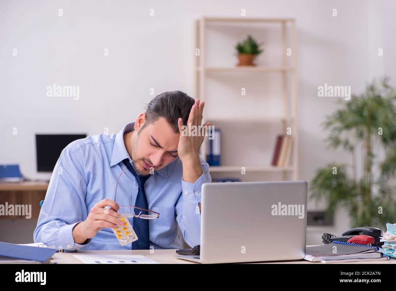 Sick male employee suffering at the workplace Stock Photo - Alamy