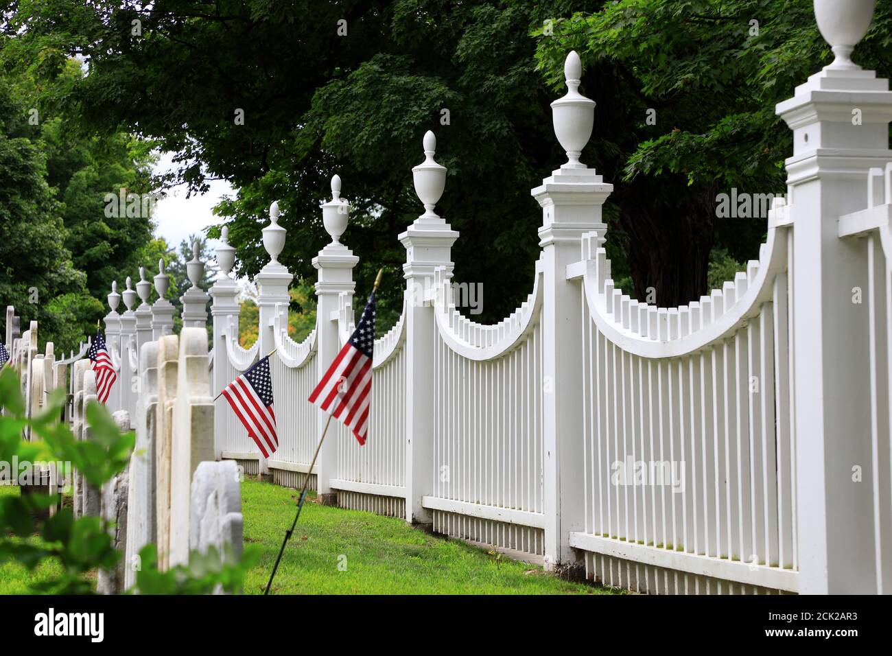 Curved white wooden fence with tombstones and US flags in Old ...