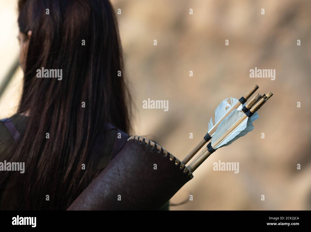 Woman archer standing with her back with quiver for arrows on blurred ...