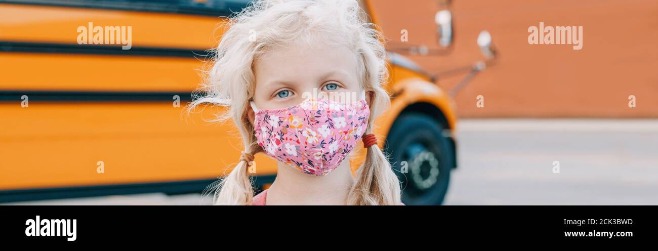 Caucasian girl student wearing face mask by yellow school bus. Kid with ...