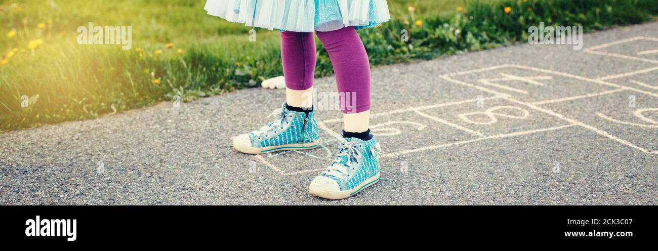 Closeup of child girl playing jumping hopscotch outdoor. Funny activity ...