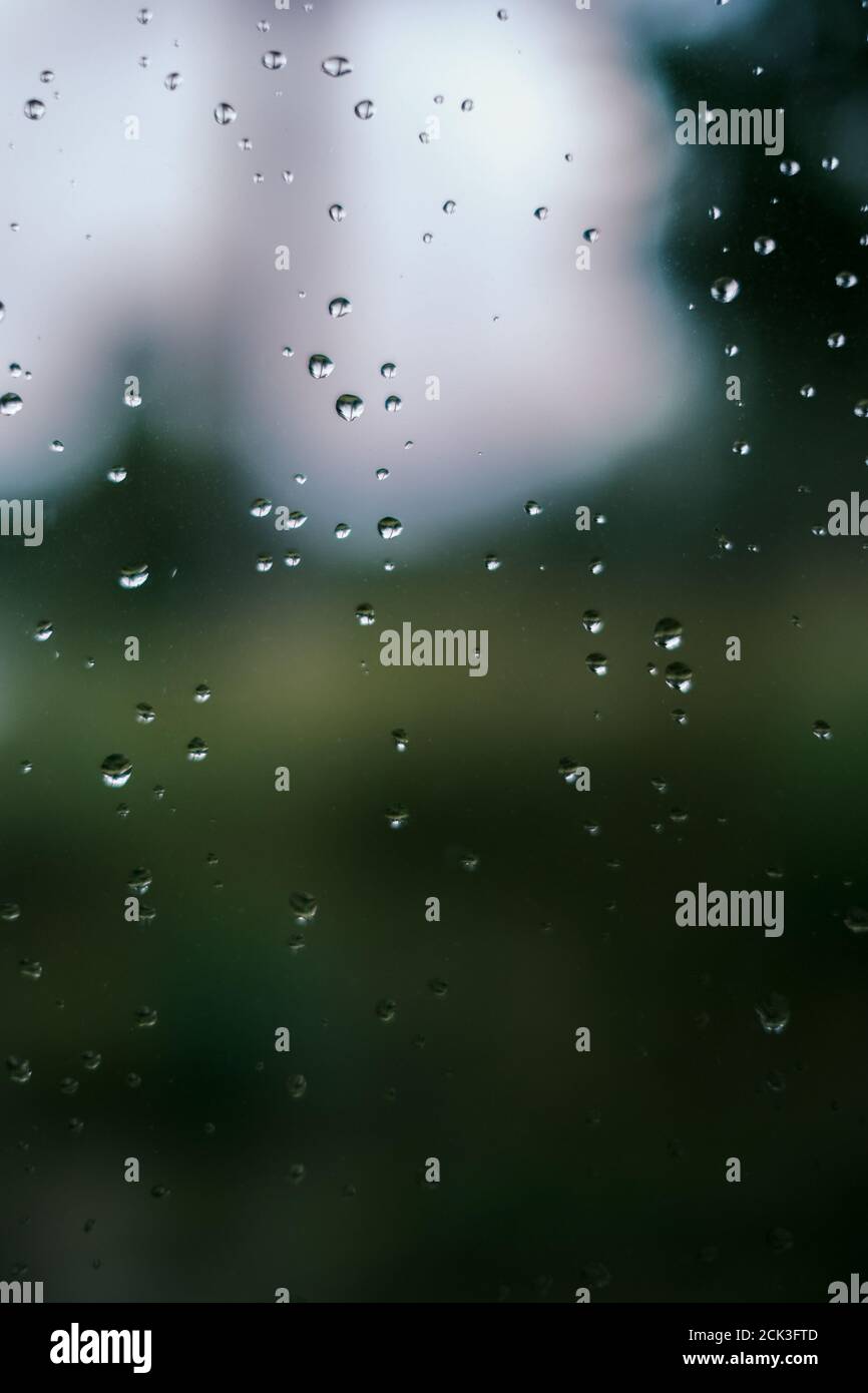Vertical shot of raindrops in a mirror surface on a blurred background ...