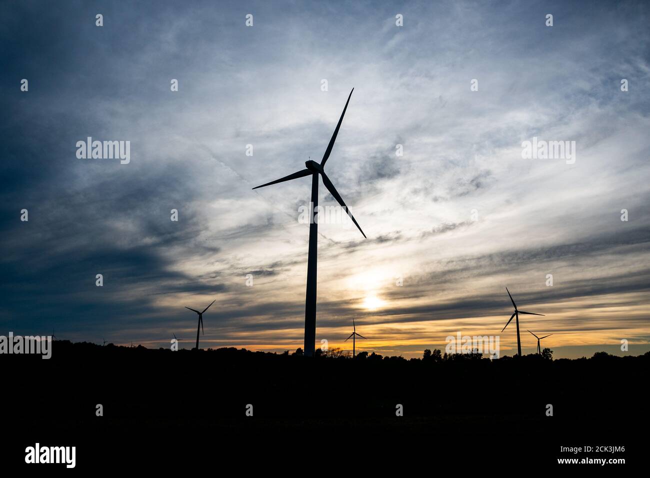 The sun sets on a field of wind turbines at a wind farm in Indiana ...
