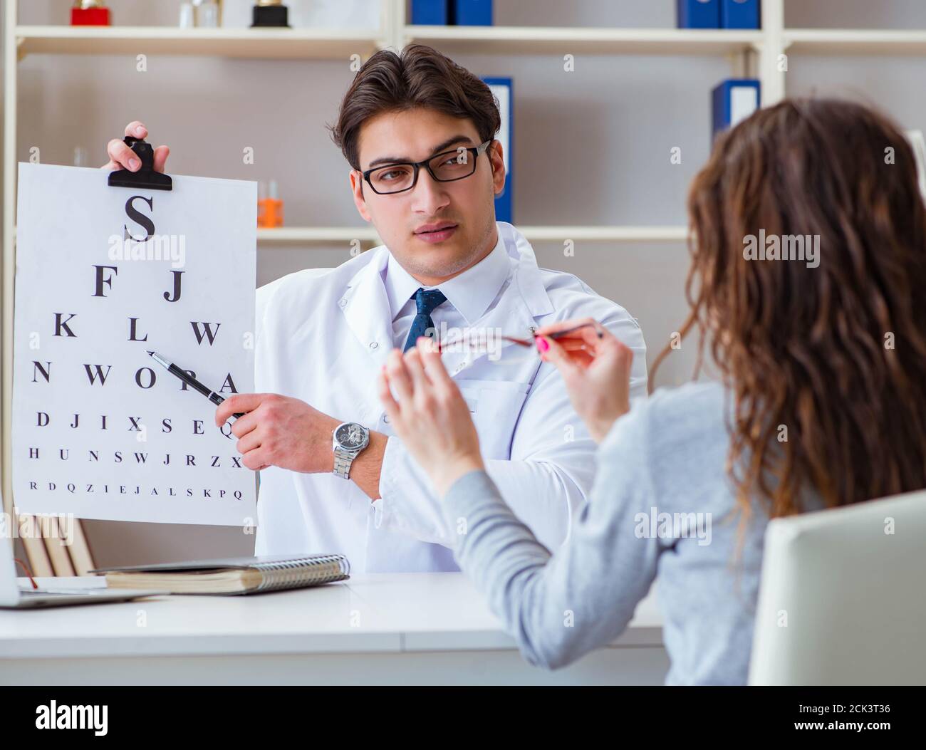 Doctor optician with letter chart conducting an eye test check Stock ...