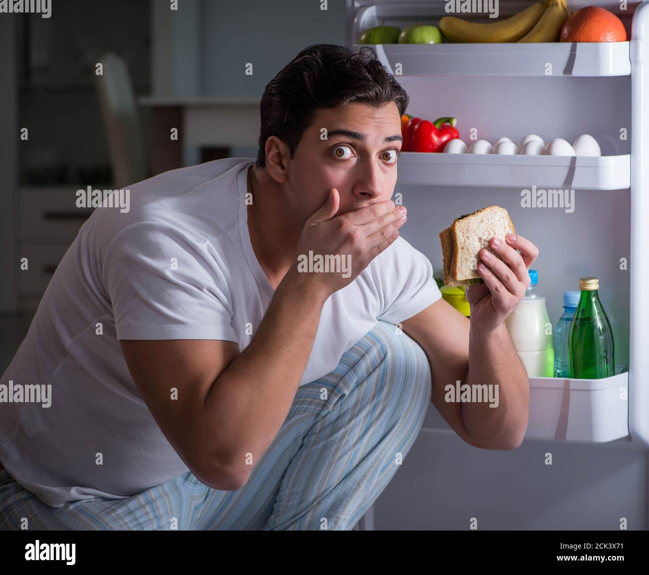 The man at the fridge eating at night Stock Photo - Alamy