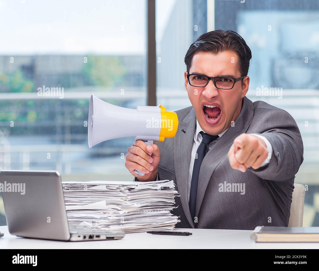 Angry businessman with loudspeaker in the office Stock Photo - Alamy