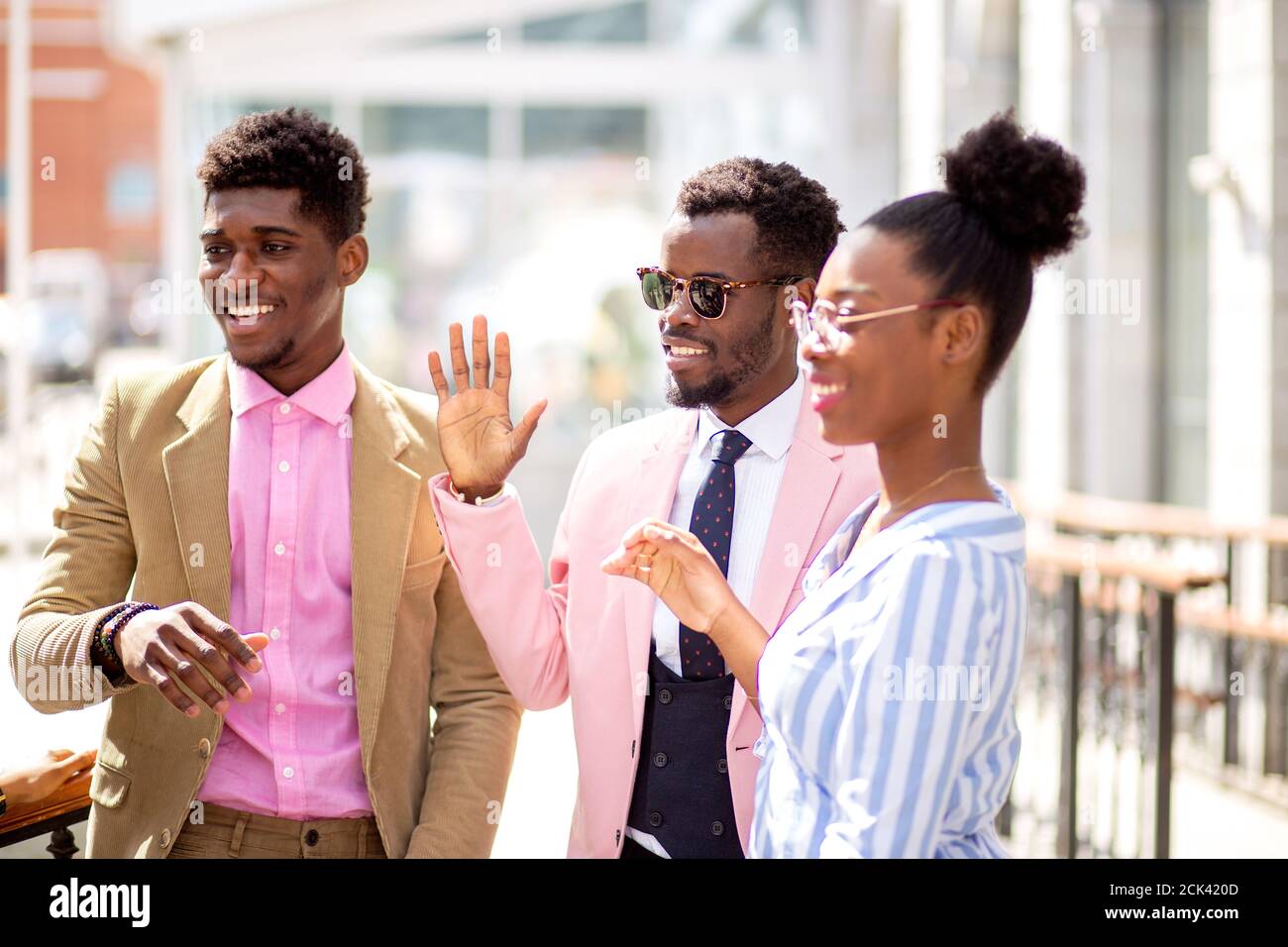 three african people are greeting their friend outdoors. hi, hello, bye ...