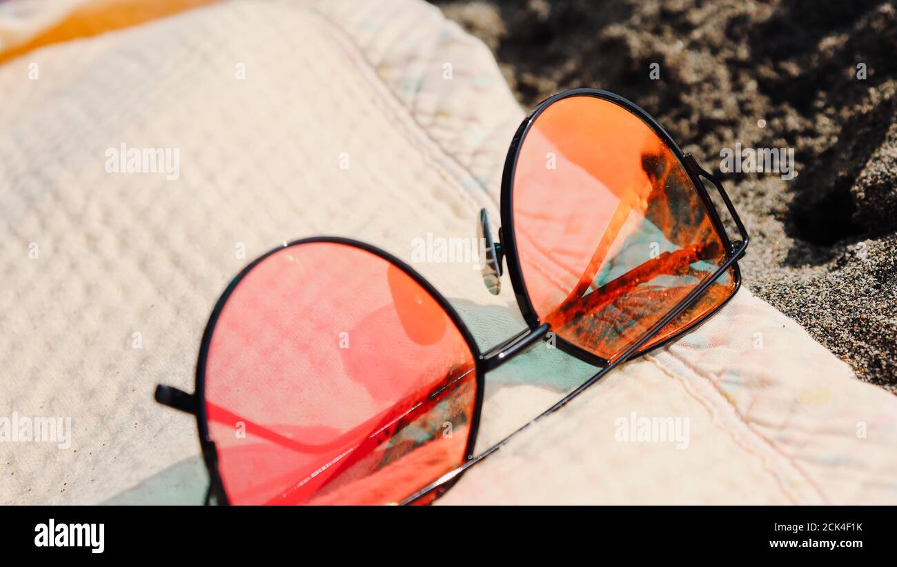 Sunglasses on a beach with reflection of summer beach with black sand ...