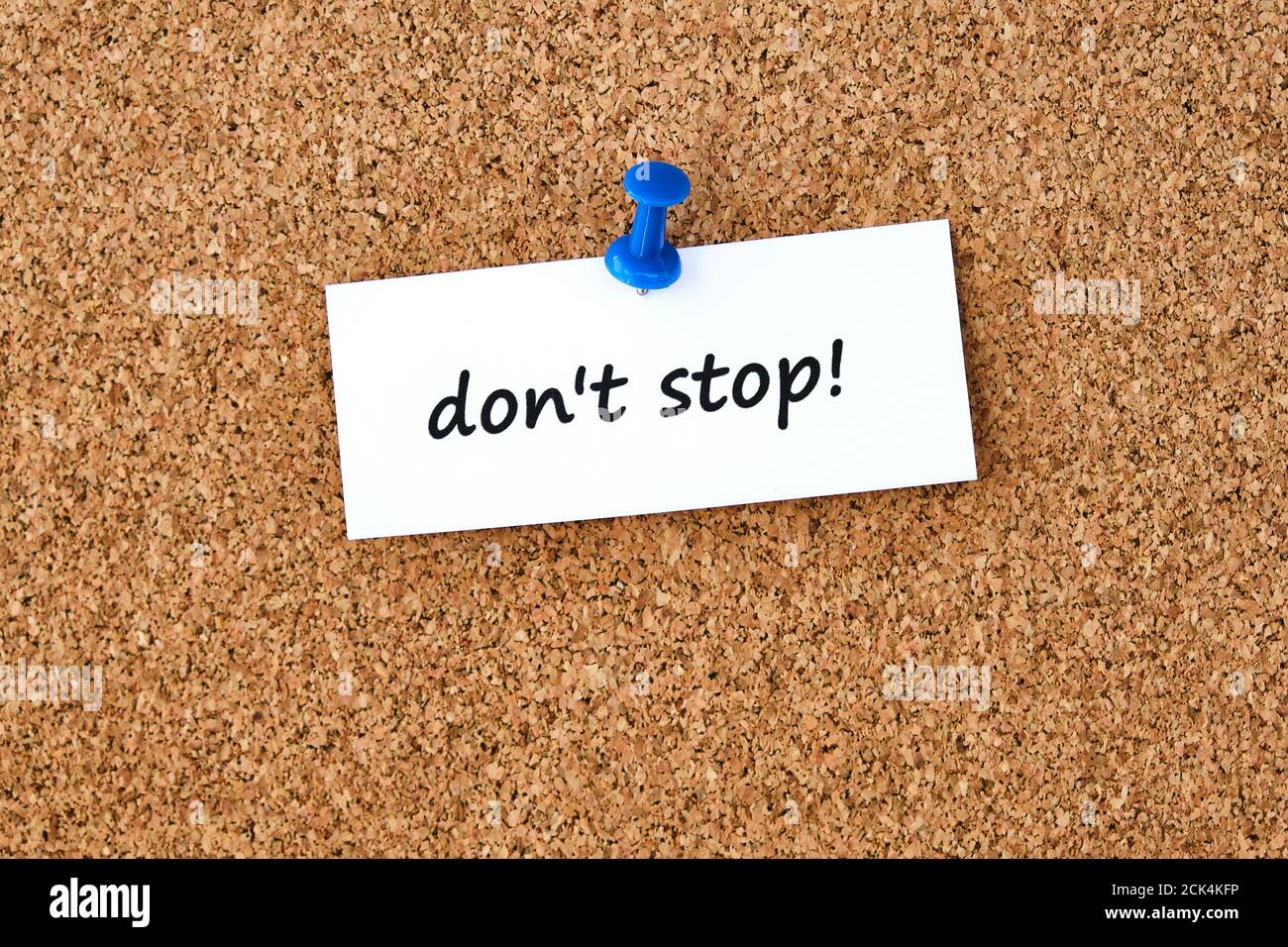 Don't stop. Text written on a piece of paper or note, cork board ...