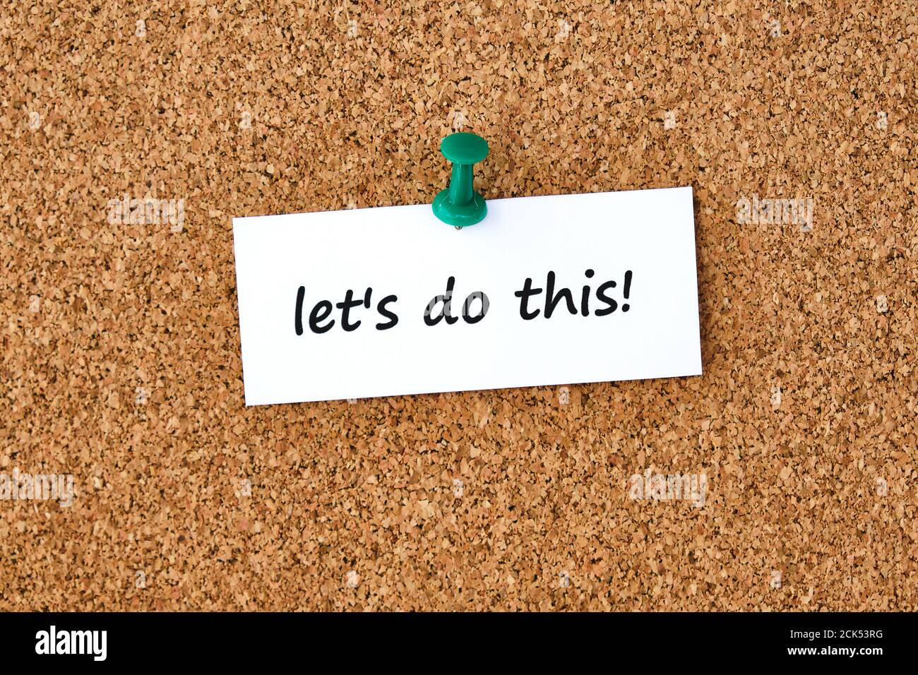 Let's do this. Text written on a piece of paper or note, cork board ...