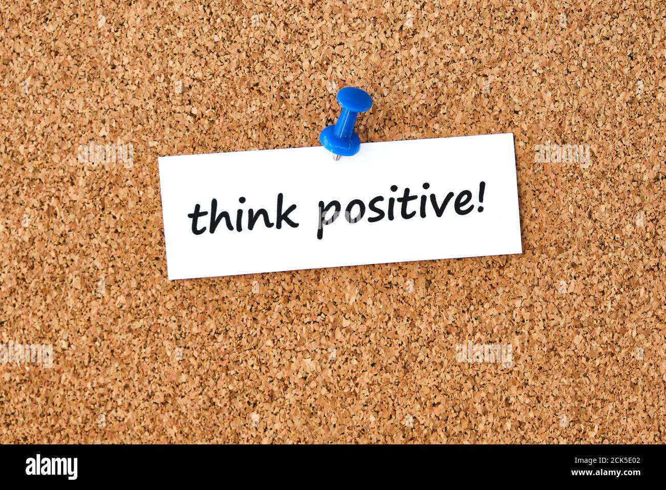 Think positive. Text written on a piece of paper or note, cork board ...