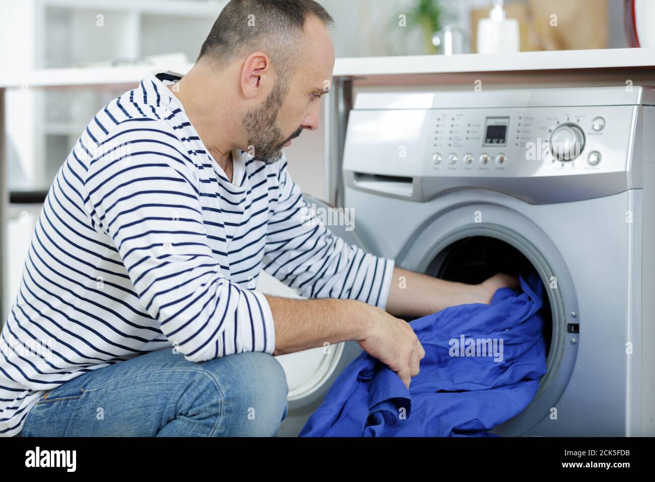 man putting color clothes into washing machine inside view Stock Photo ...