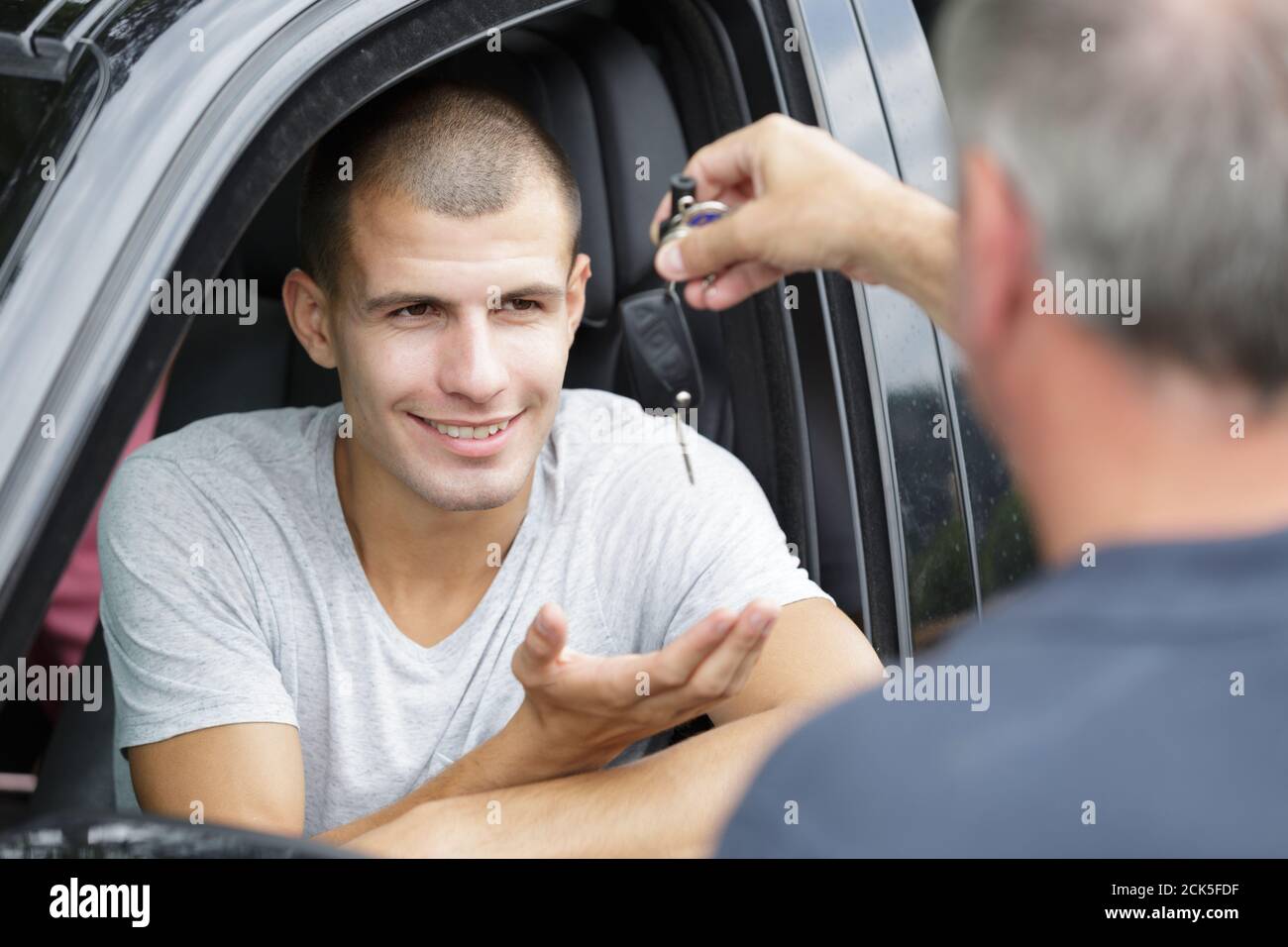 elderly man giving car key to younger man Stock Photo - Alamy