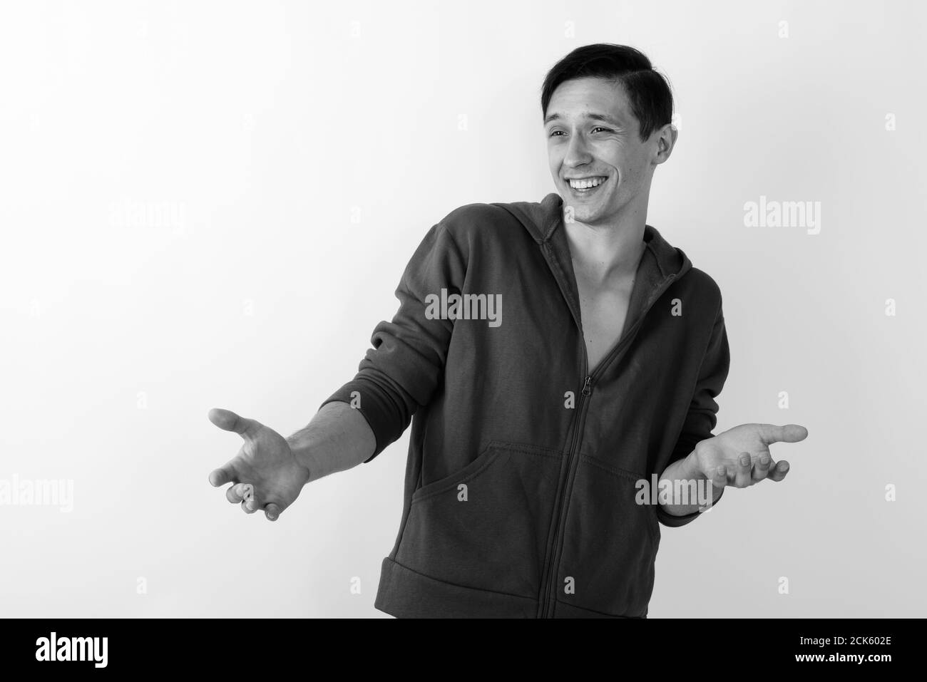 Studio shot of happy young handsome man smiling while looking confused ...