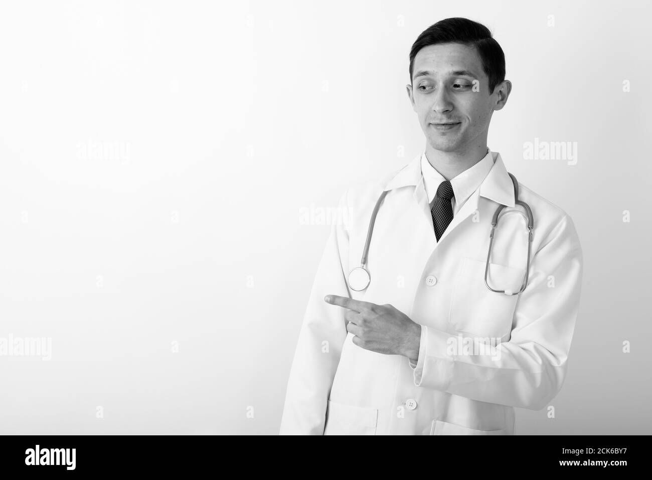 Studio shot of young handsome man doctor pointing to the side against ...