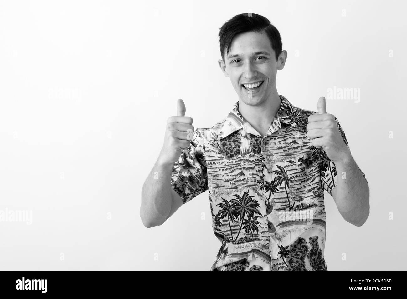 Studio shot of young happy tourist man smiling while giving thumbs up ...