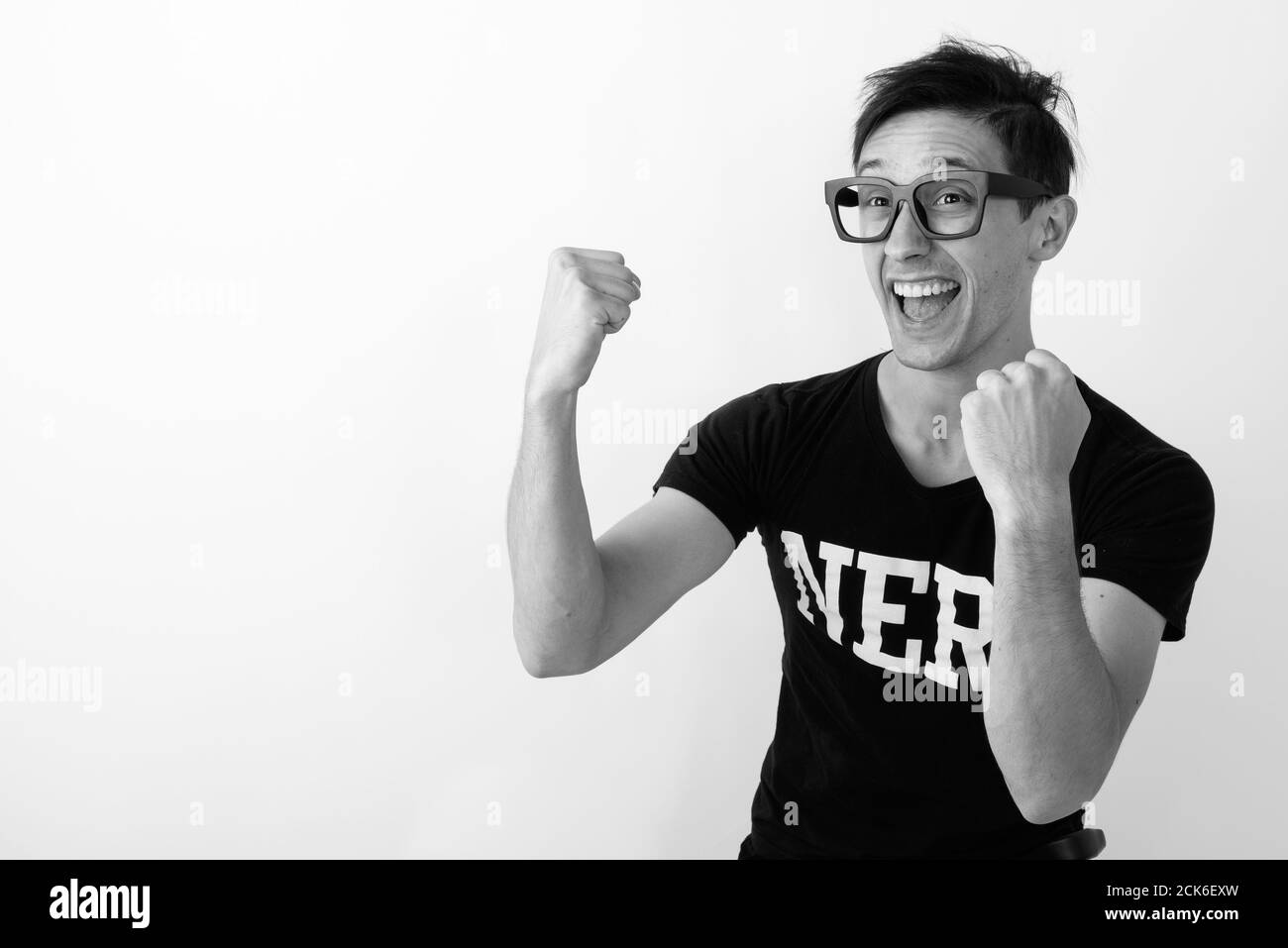 Studio shot of young happy nerd man smiling while thinking and looking ...