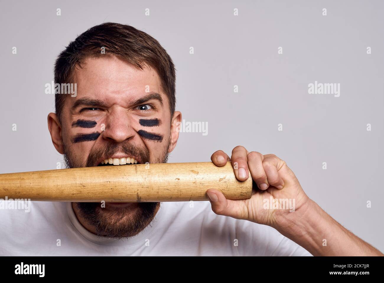 Aggressive man with a baseball bat in his hands on a gray background ...