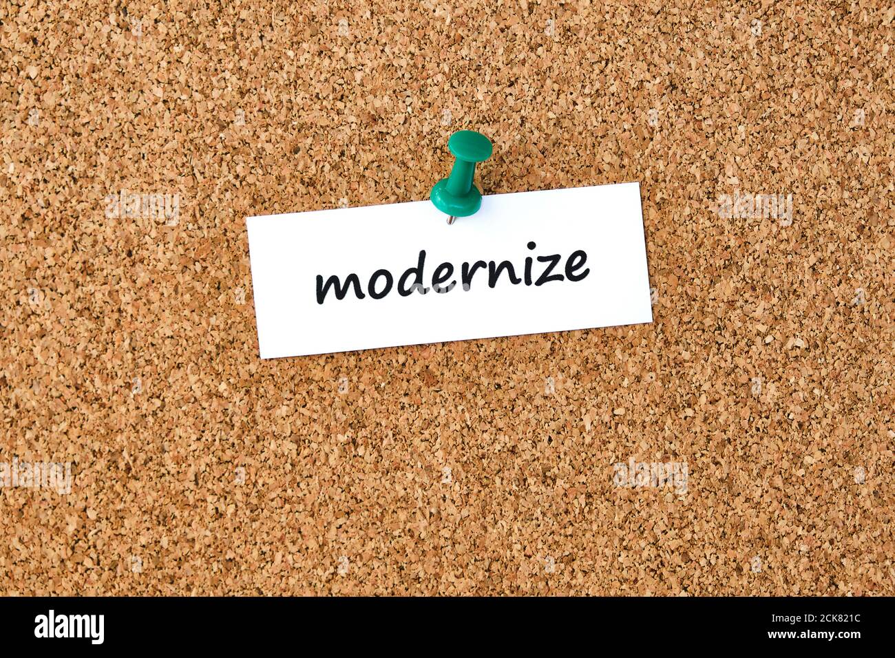 Modernize. Word written on a piece of paper or note, cork board ...