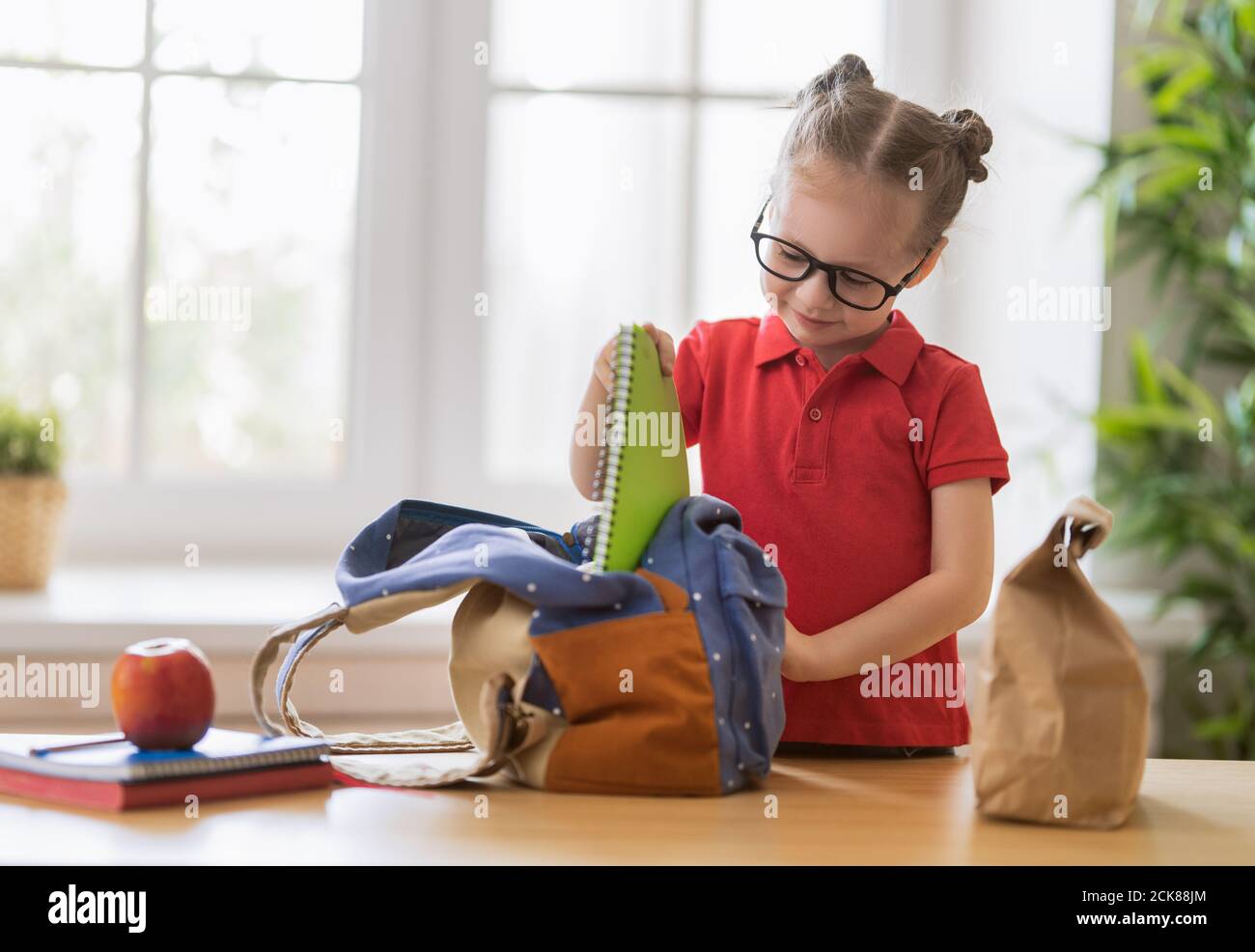 Happy child preparing for school. Little girl is putting things into ... Happy child preparing for school. Little girl is putting things into ...