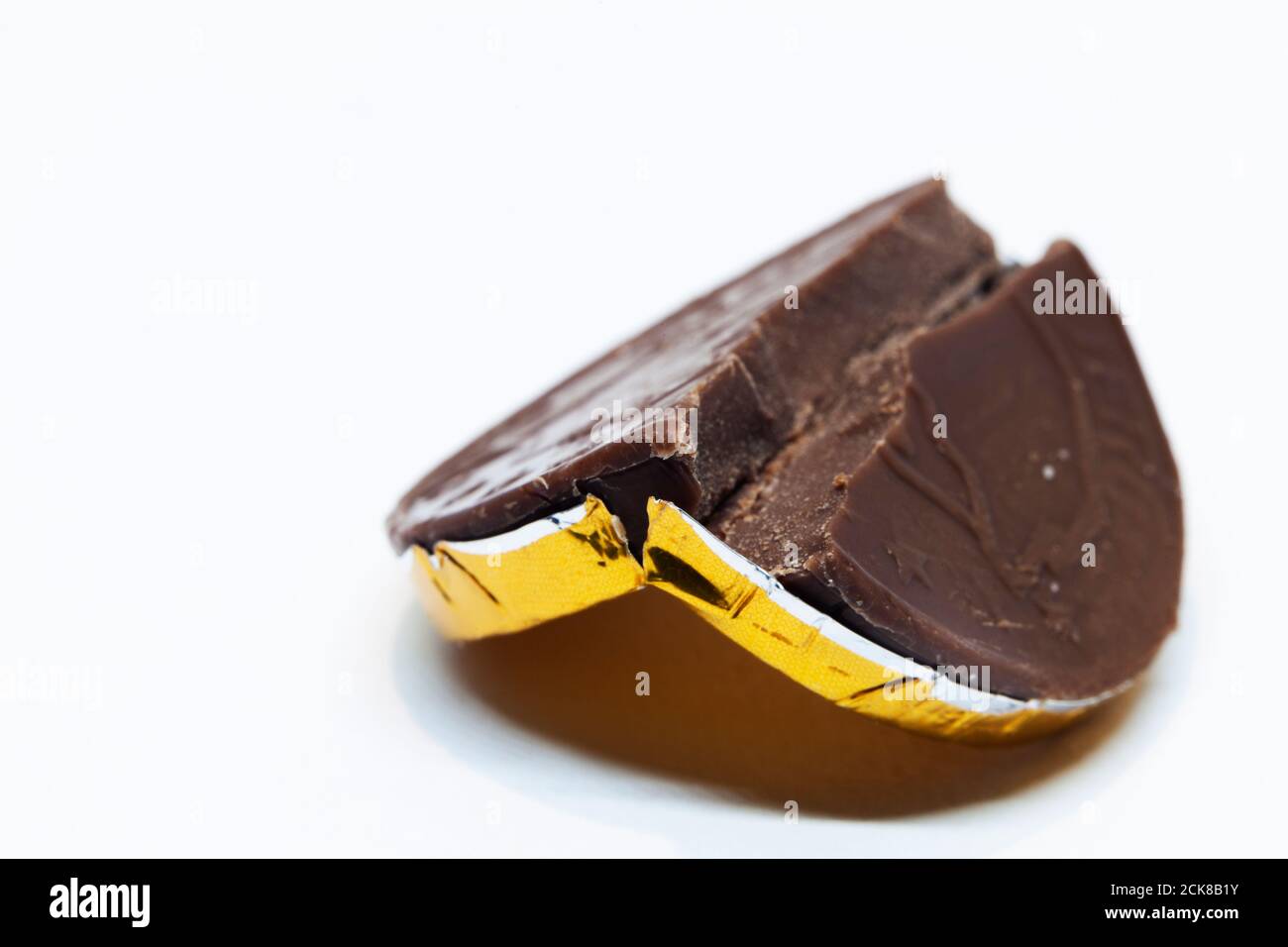 a chocolate coin broken in two on white background Stock Photo - Alamy