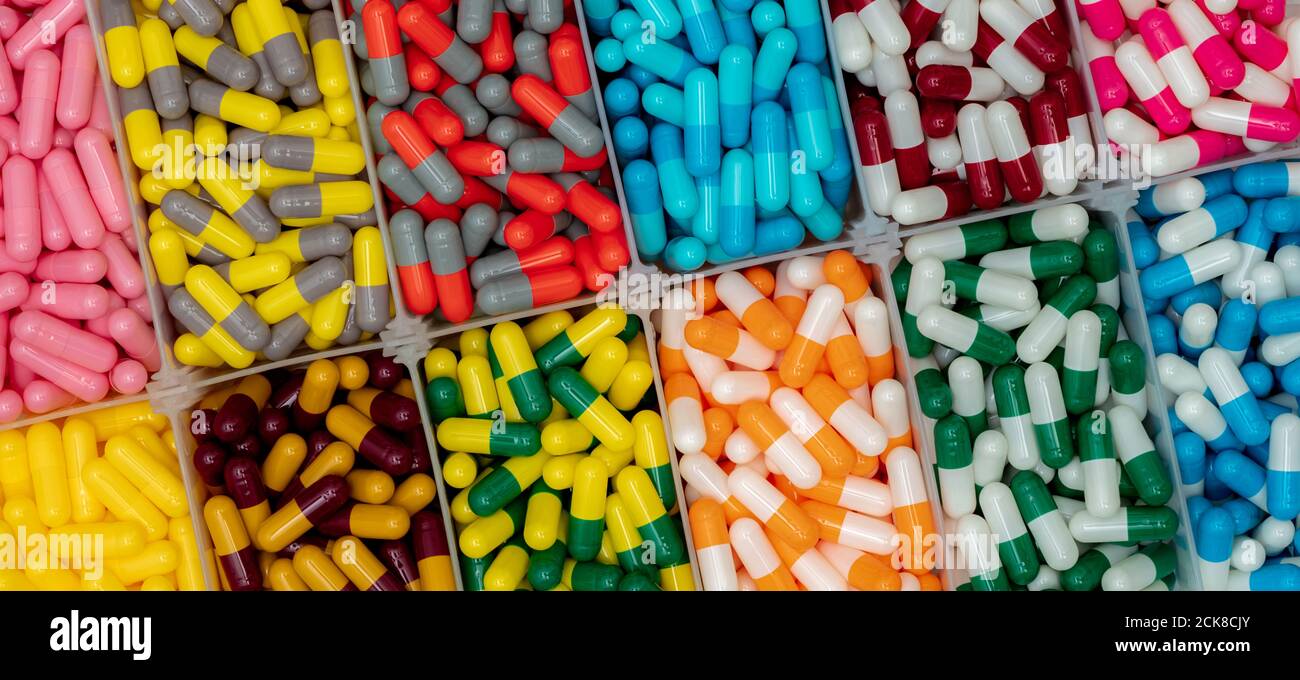 Colorful capsule pills in plastic box. Pharmaceutical industry. Pink ...