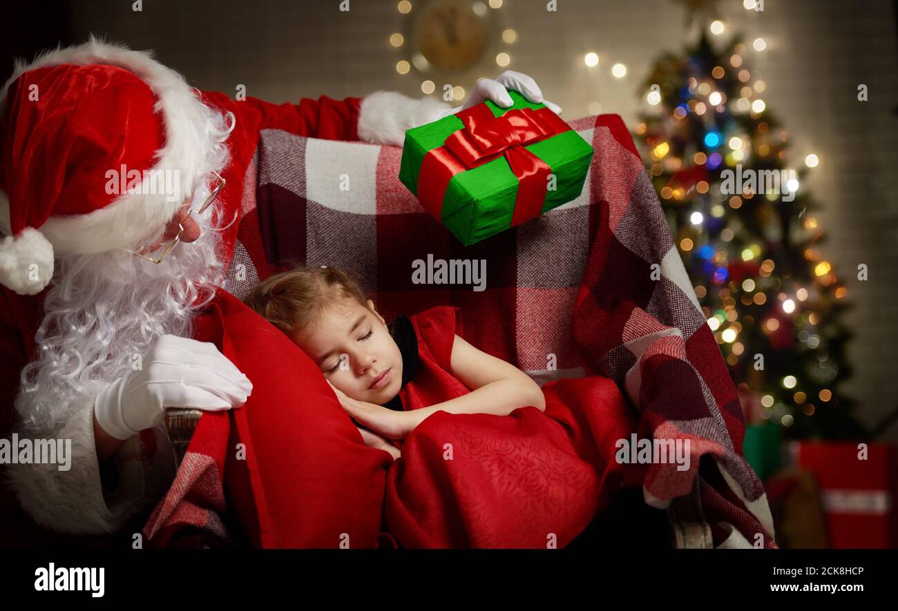 Santa Claus making a surprise for little sleeping girl Stock Photo - Alamy