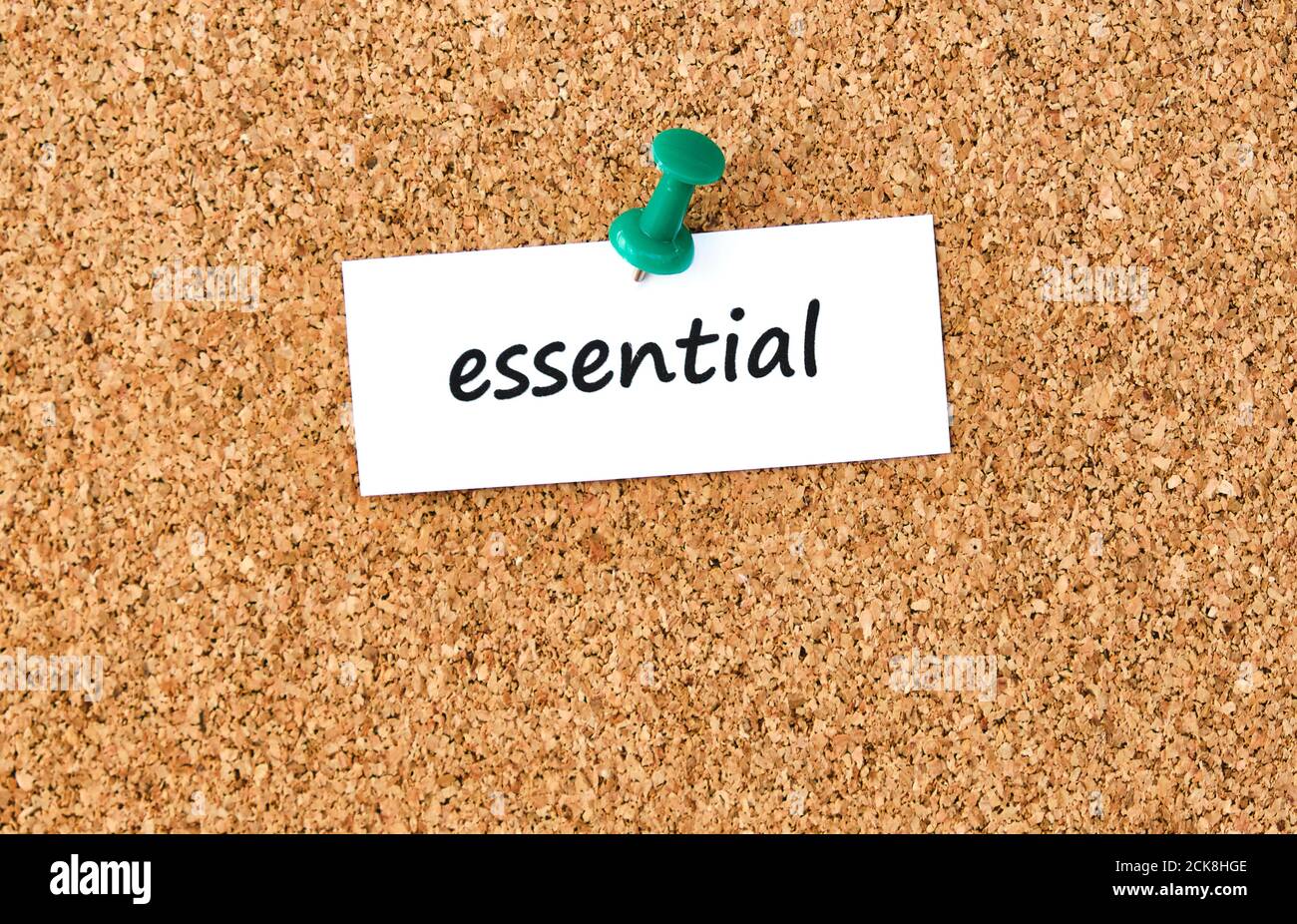 Essential. Word written on a piece of paper or note, cork board ...